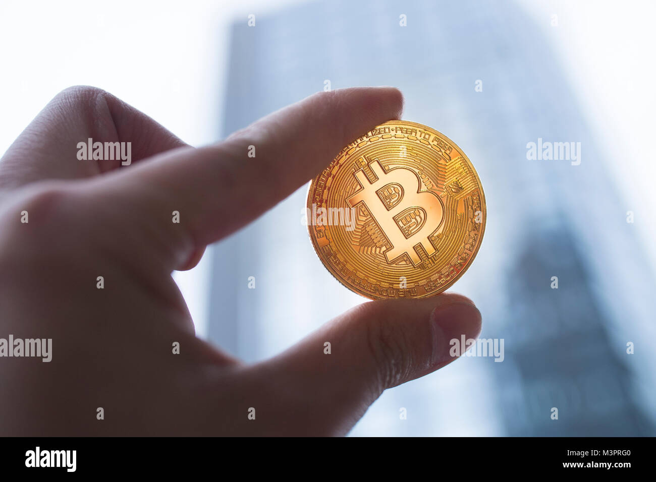 hand holding one bitcoin with the city high office building background ...