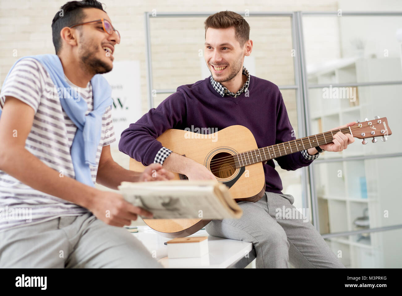 Young man playing guitar at office hi-res stock photography and images ...