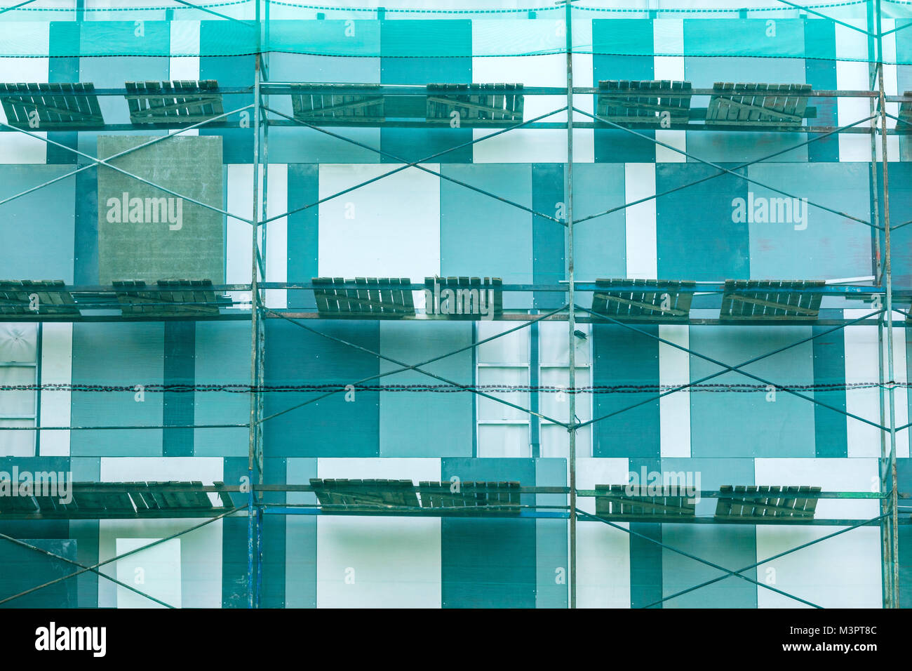 building is covered with scaffolds and green safety net. construction ...