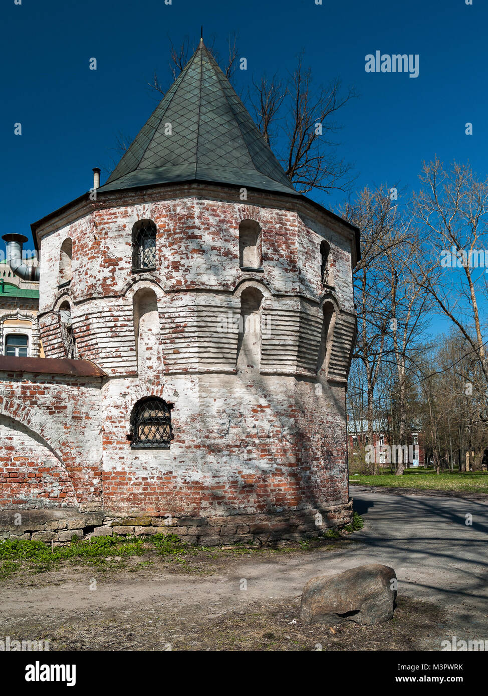 White corner tower of red brick with a green pointed roof in a ruinous ...