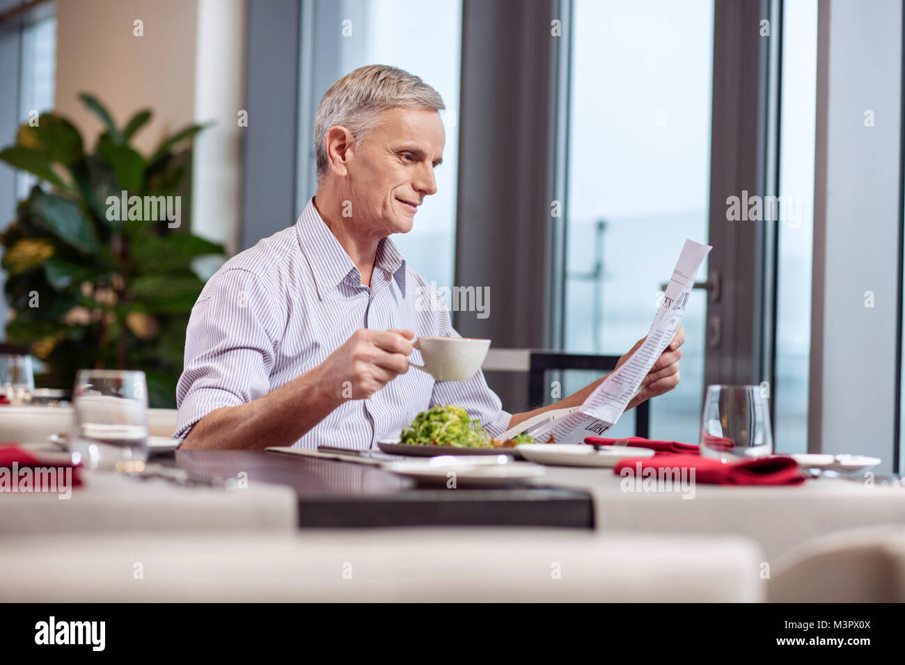 Positive mature man sipping coffee Stock Photo - Alamy