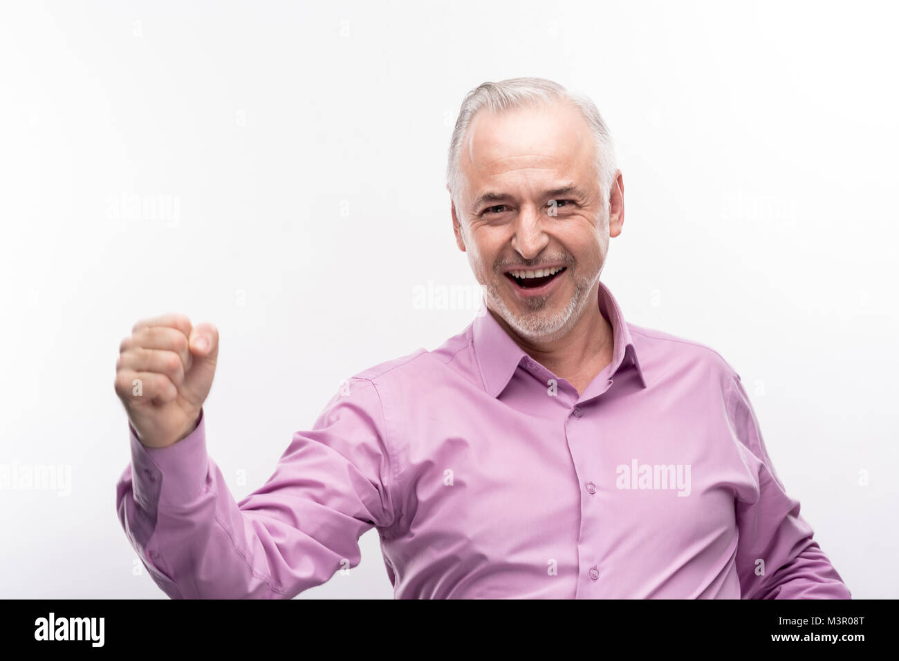Cheerful grey-haired man clenching his fist in triumph Stock Photo - Alamy