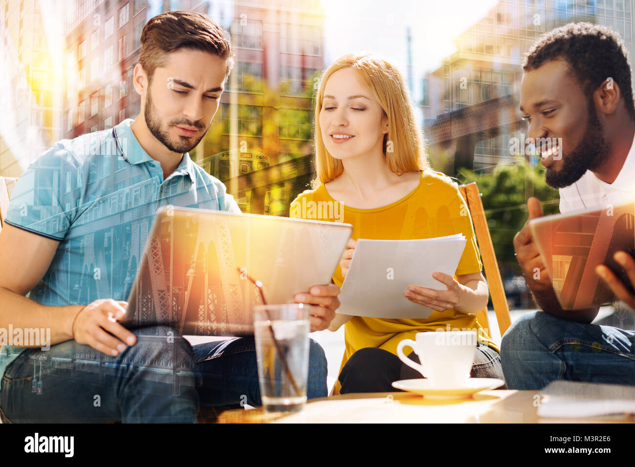 Clever friends sitting with their gadgets and talking Stock Photo - Alamy
