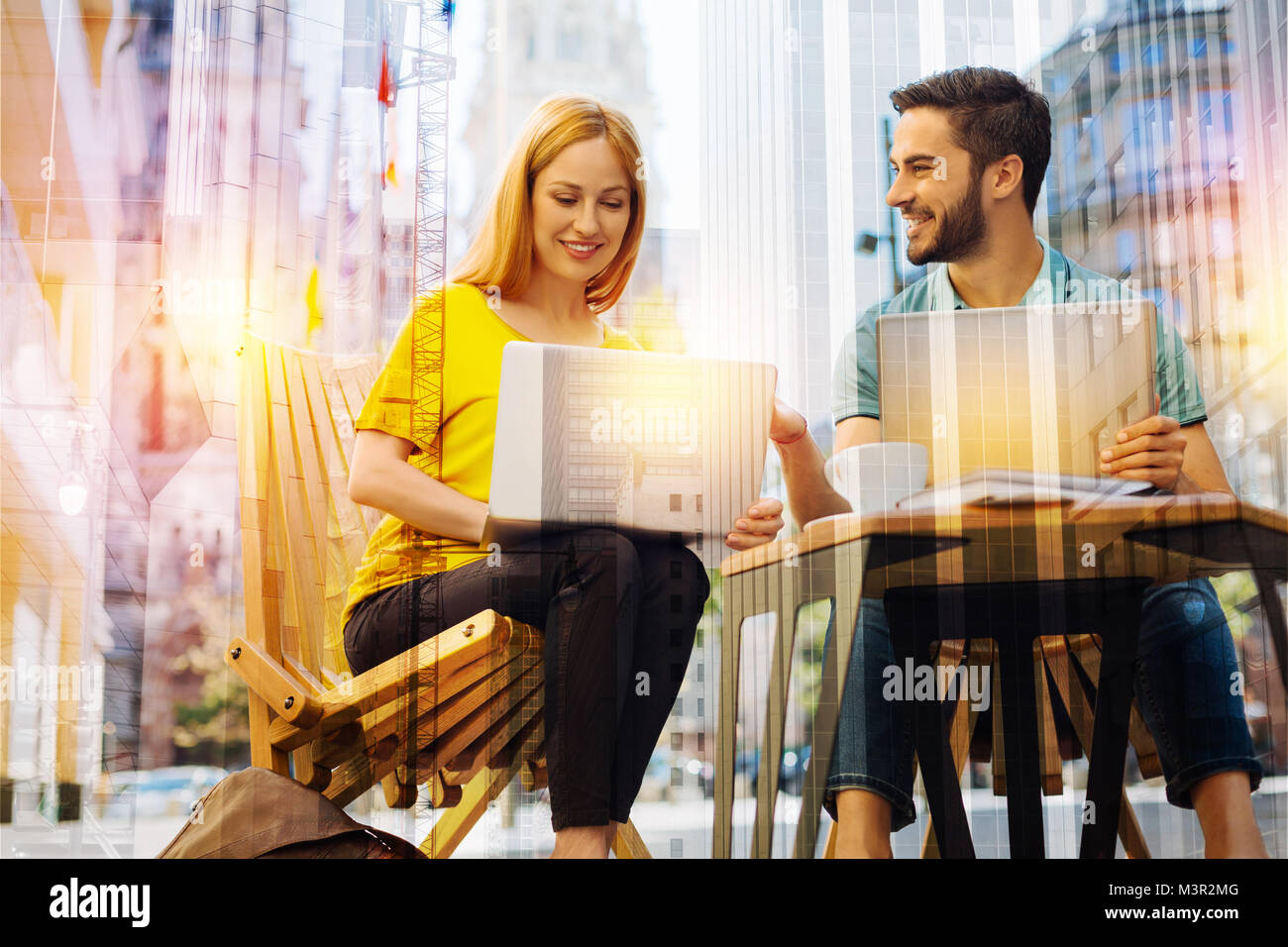 Emotional coworkers smiling while sitting in a cafe and working Stock ...