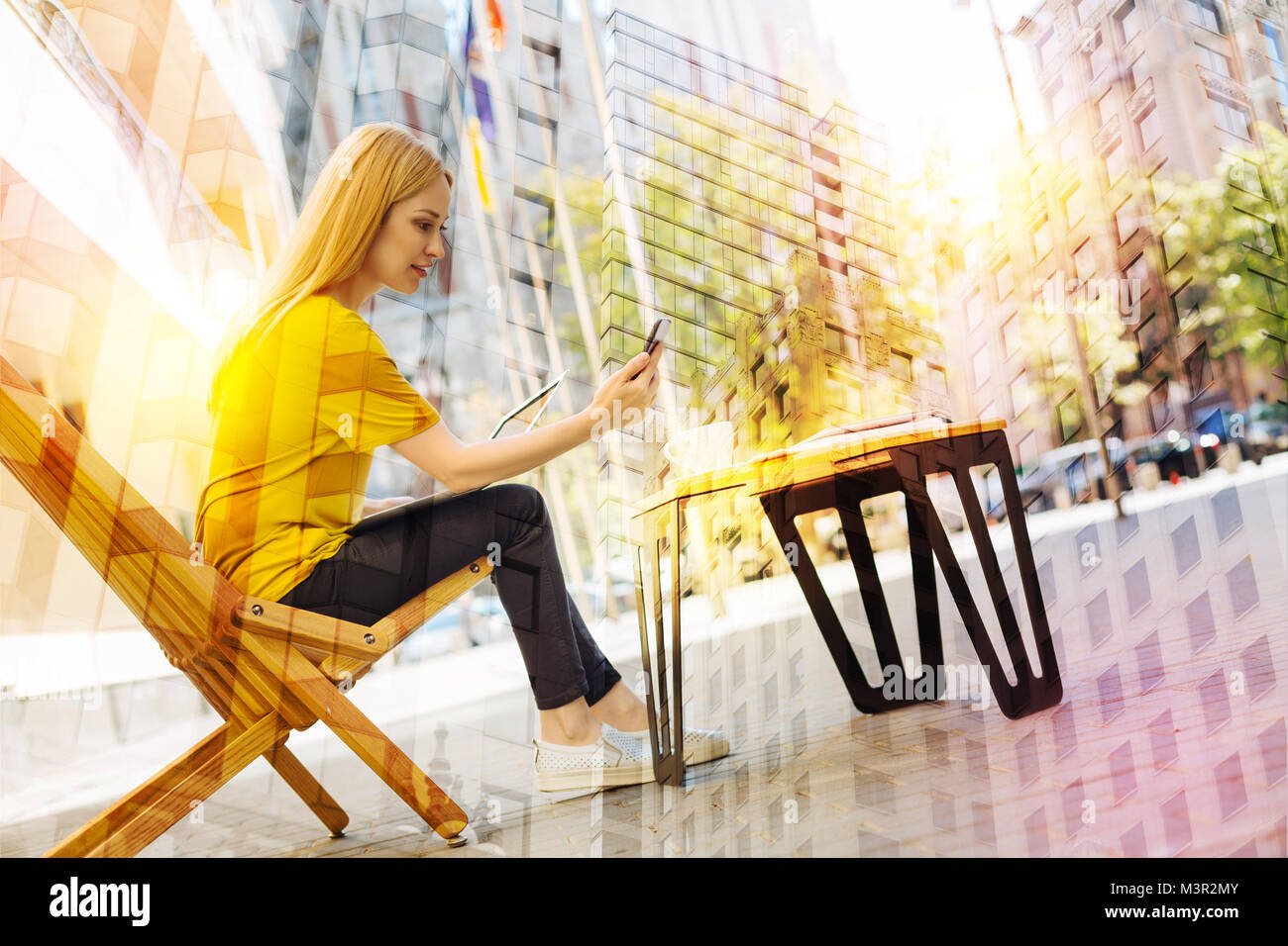 Calm young woman reading messages while sitting alone Stock Photo - Alamy