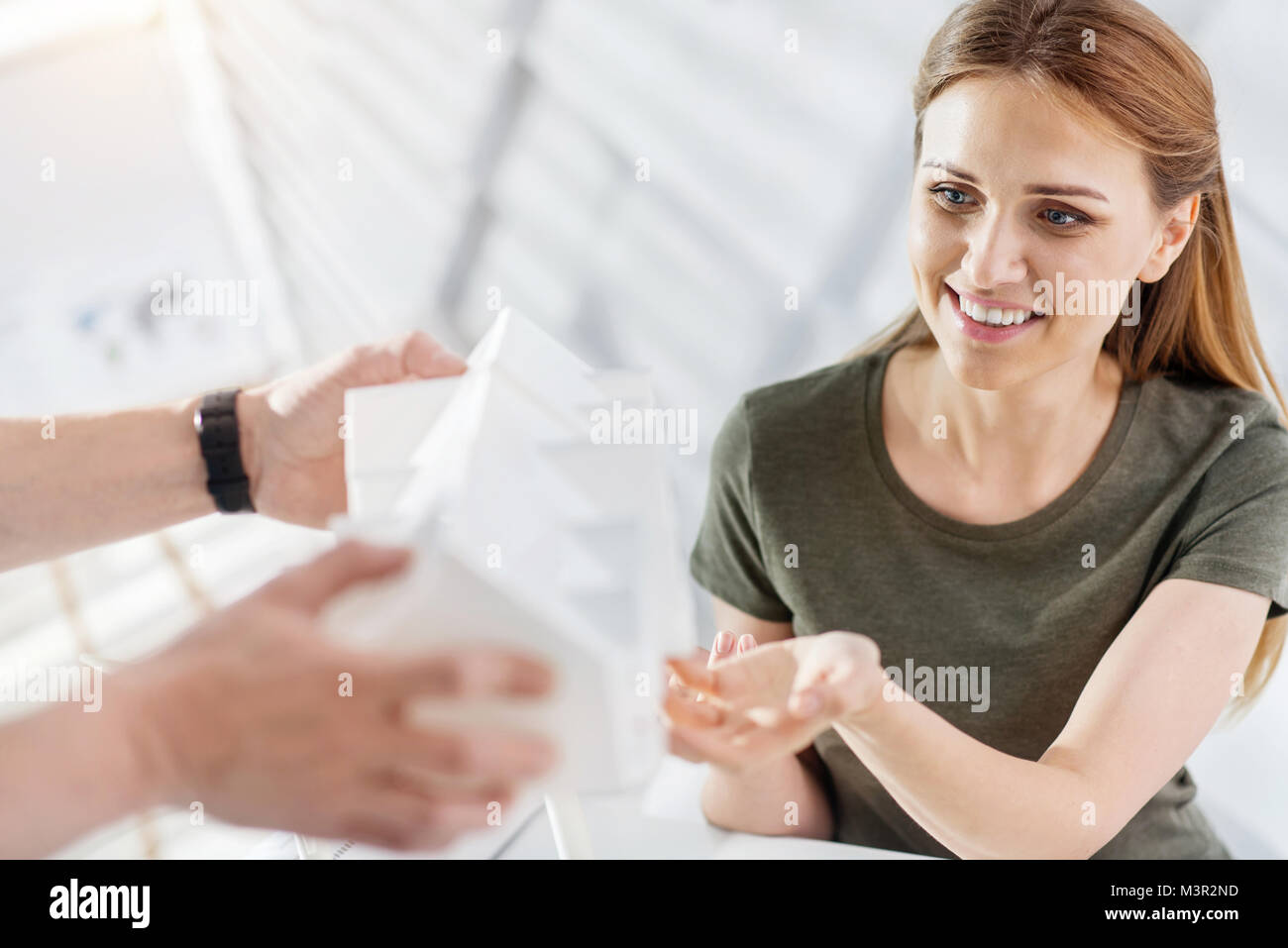 Smiling architect looking at a house miniature Stock Photo - Alamy