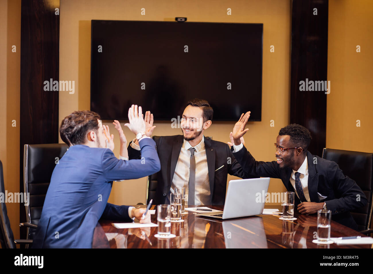 business team giving high fives gesture as they laugh and cheer their ...