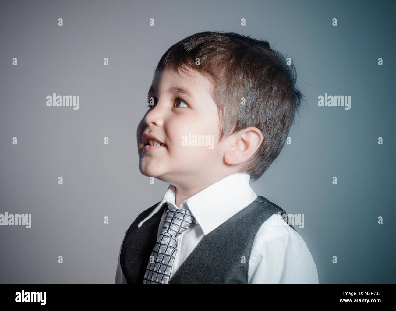 little businessman, brown-haired boy dressed in suit and tie with faces ...