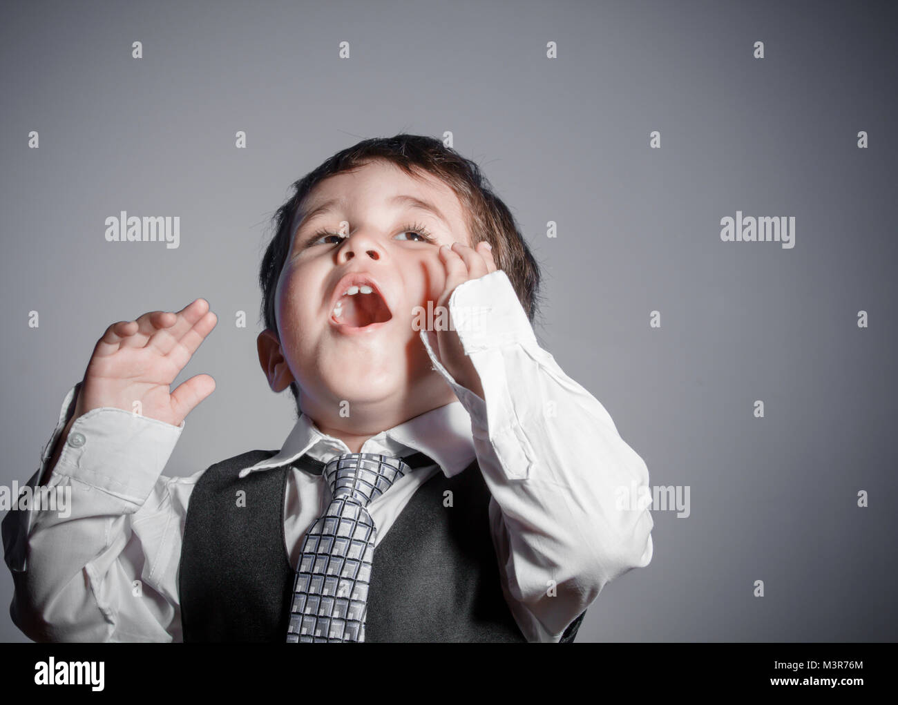 little businessman, brown-haired boy dressed in suit and tie with faces ...