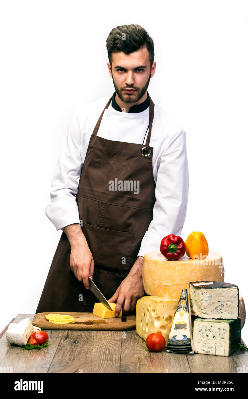 young chef cuts the cheese on the table isolated on white background ...