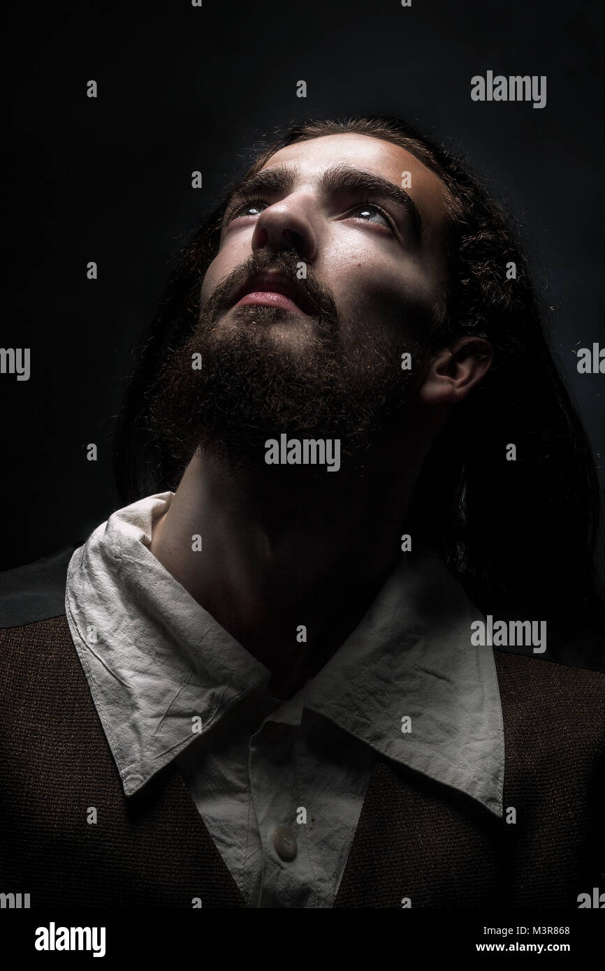 low key portrait of bearded medieval peasant looking at the top to the ...