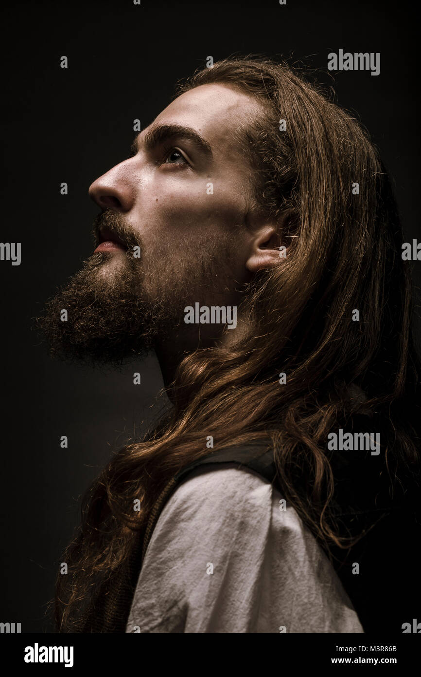 low key portrait of bearded medieval peasant looking at the top to the ...