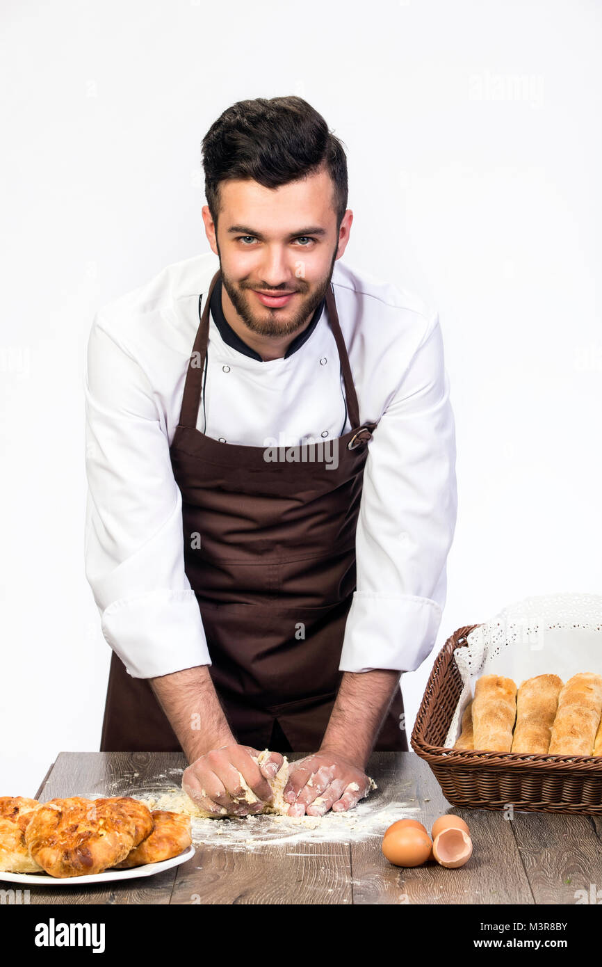 a man in an apron prepares the dough for baking, Cook model on a white ...