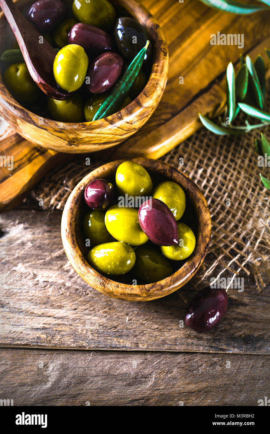 olives on olive branch. Wooden table with olives in bowl Stock Photo ...