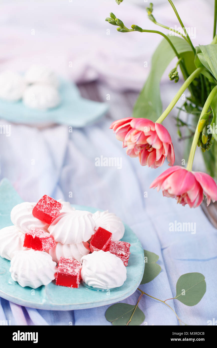 close-up of marshmallows and red marmalade in a blue plate on fabric ...