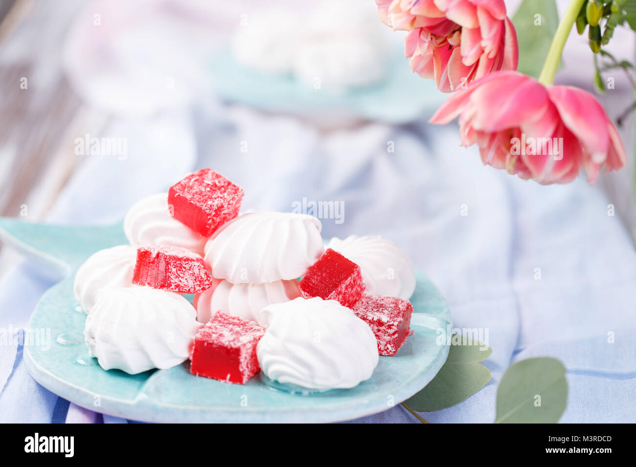 close-up of marshmallows and red marmalade in a blue plate on fabric ...