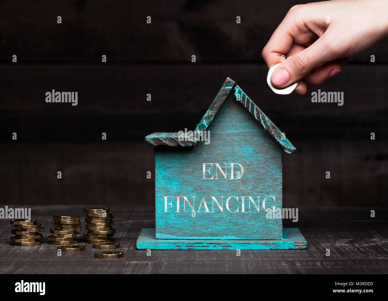 Wooden house model with coins next to it and hand holding the coin with ...