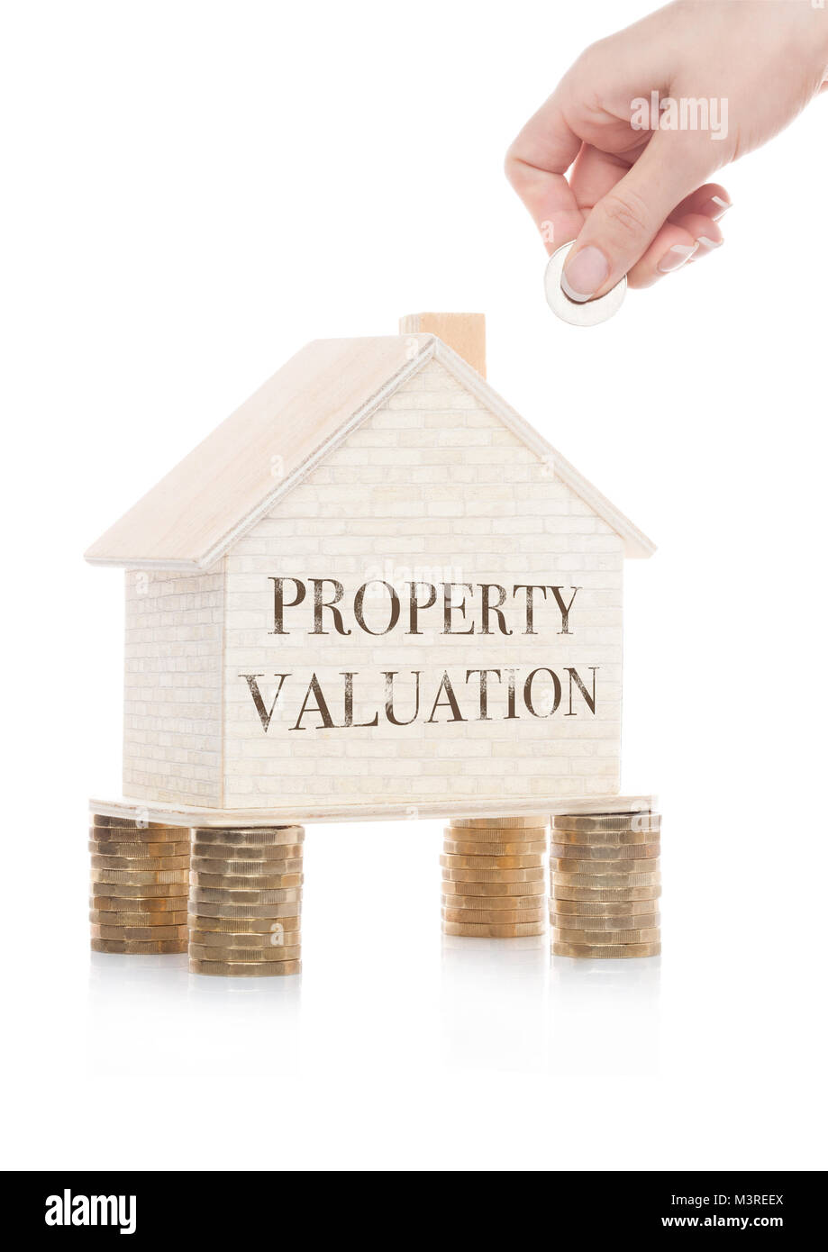 Wooden house model standing on coins and hand holding the coin with ...