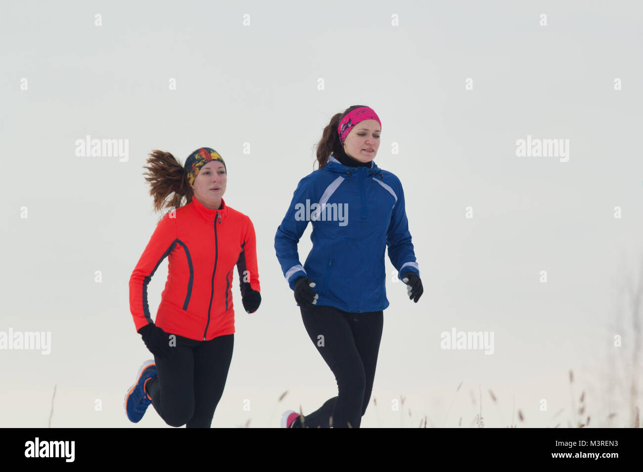 Two young female athletes running in winter Stock Photo - Alamy