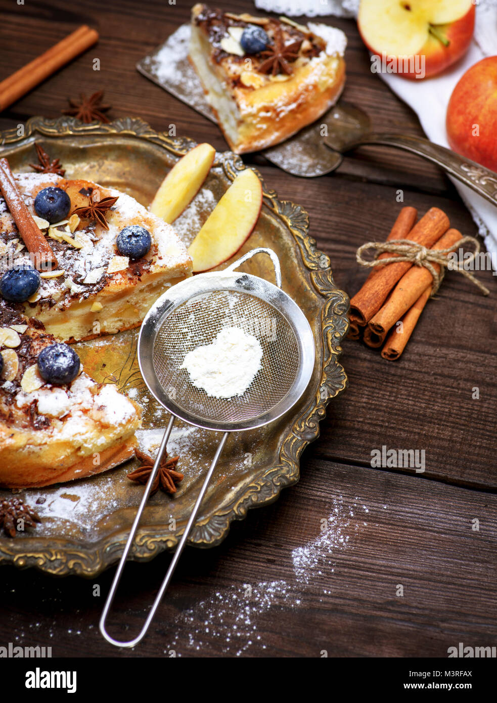 baked round apple pie and iron sieve with powdered sugar, top view ...