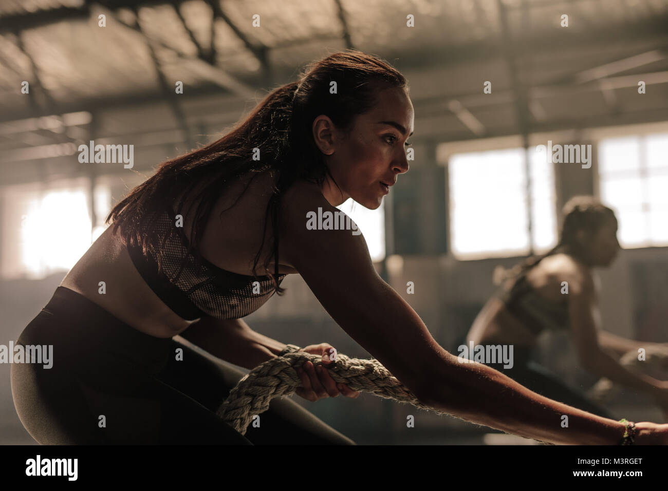 Two young women doing exercises with rope at a gym. fitness females ...