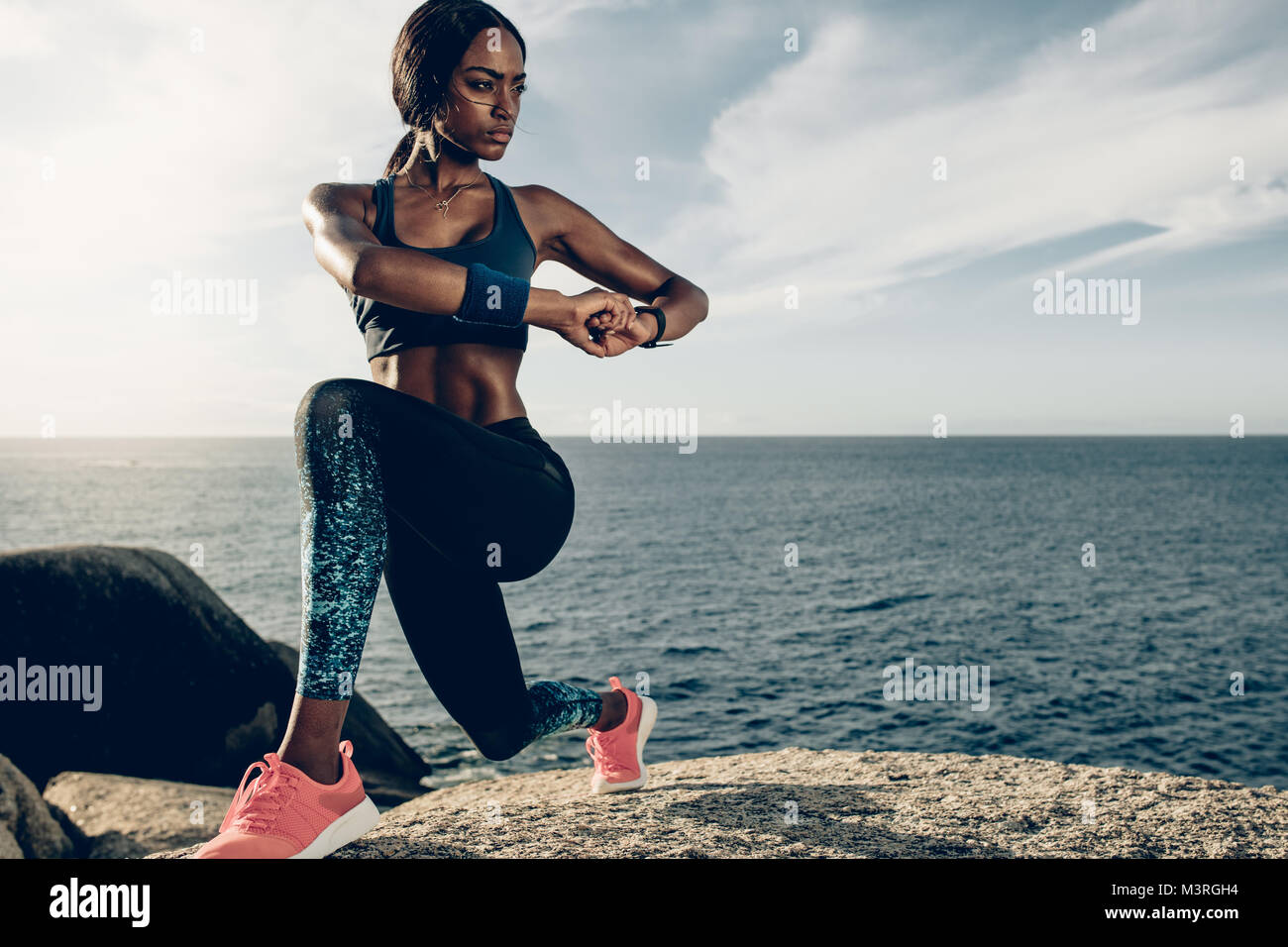 African woman doing stretching exercises by the beach. Female doing ...
