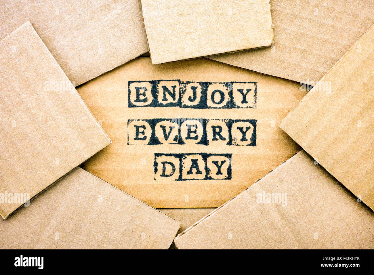 Words Enjoy Every Day make by black alphabet stamps on cardboard with ...