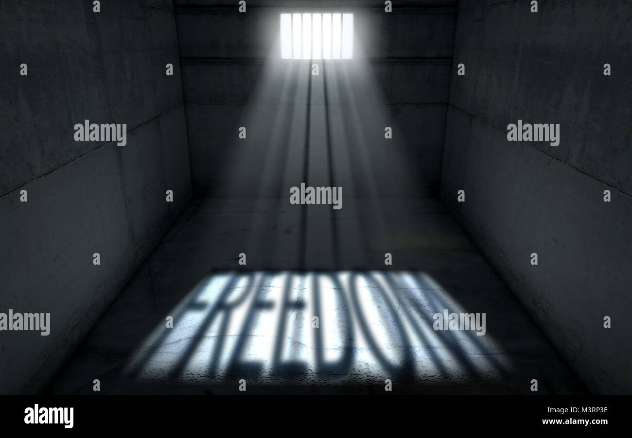 A jail cell interior with a barred up window and light rays penetrating through it casting an ...