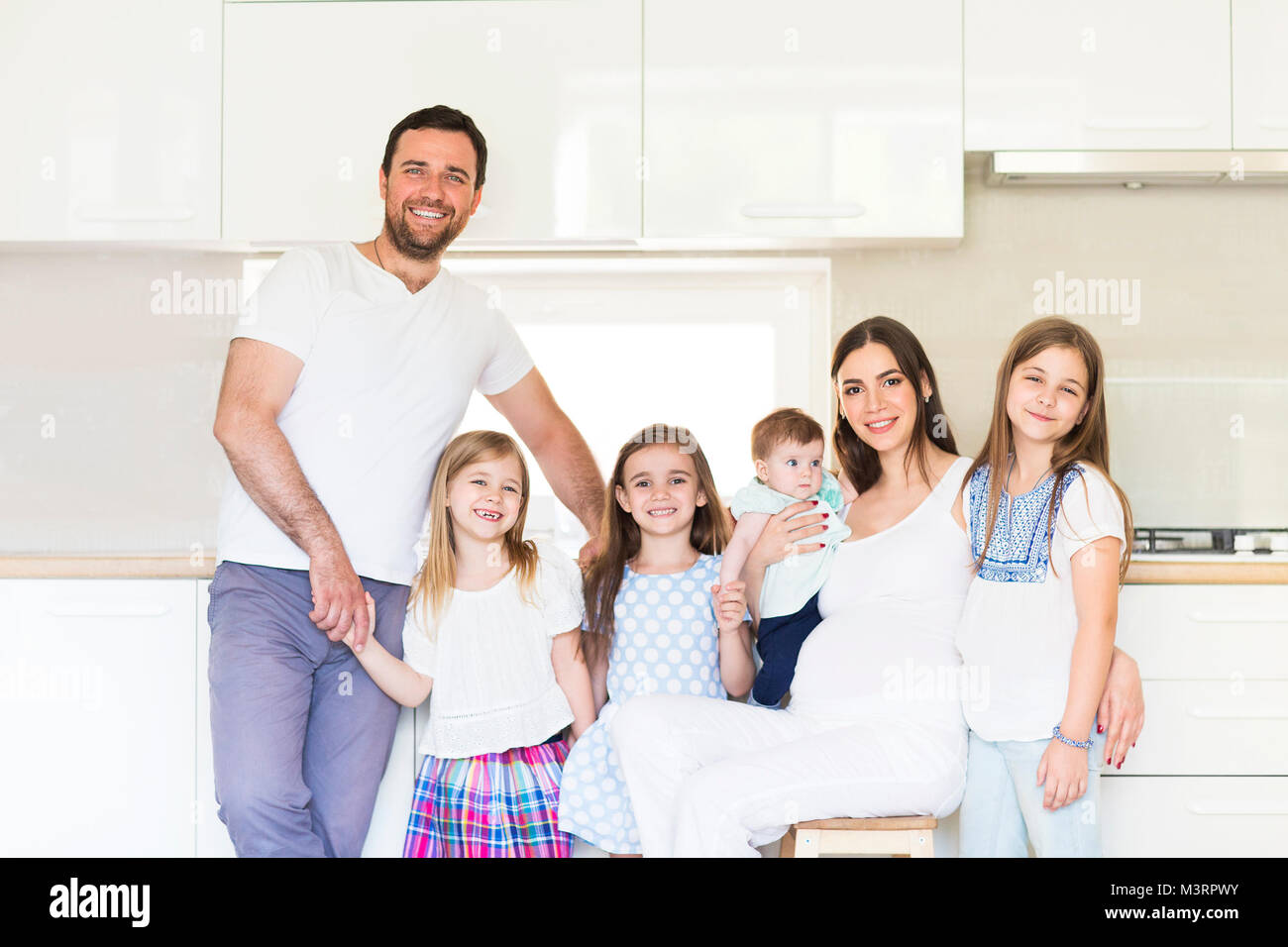 Adorable young big family embracing on kitchen. Happiness and love ...