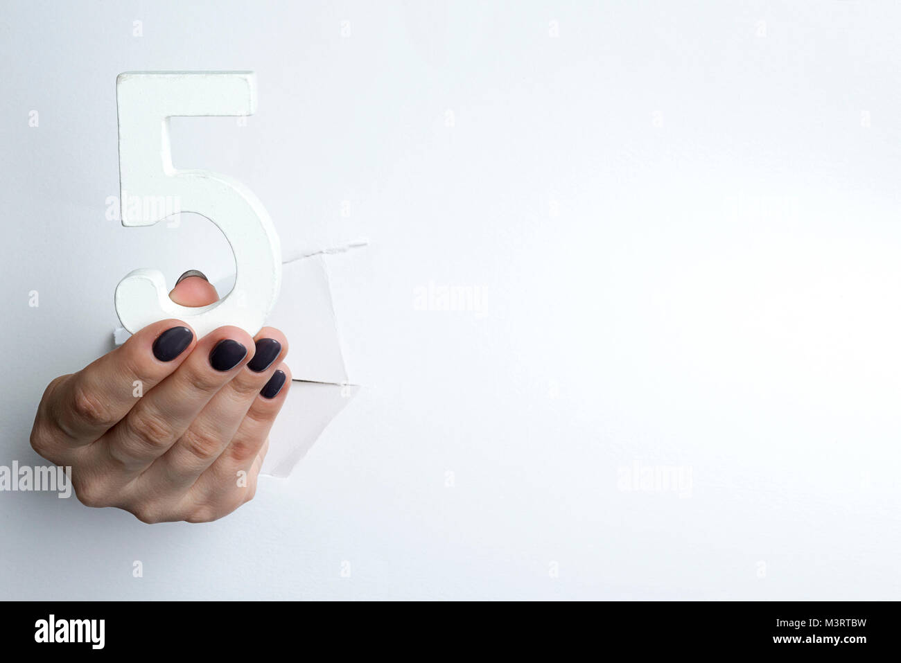 Female hand holding up the number 5 against a white background ...