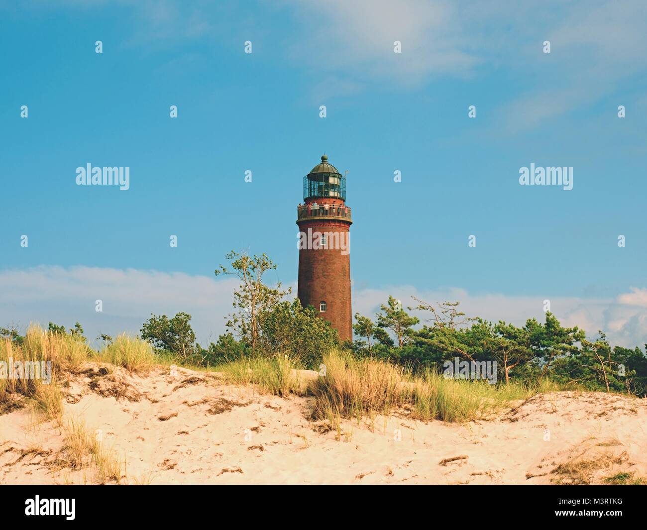 Old lighthouse at Prerow above dunes and pine tree before sunset. Tower ...
