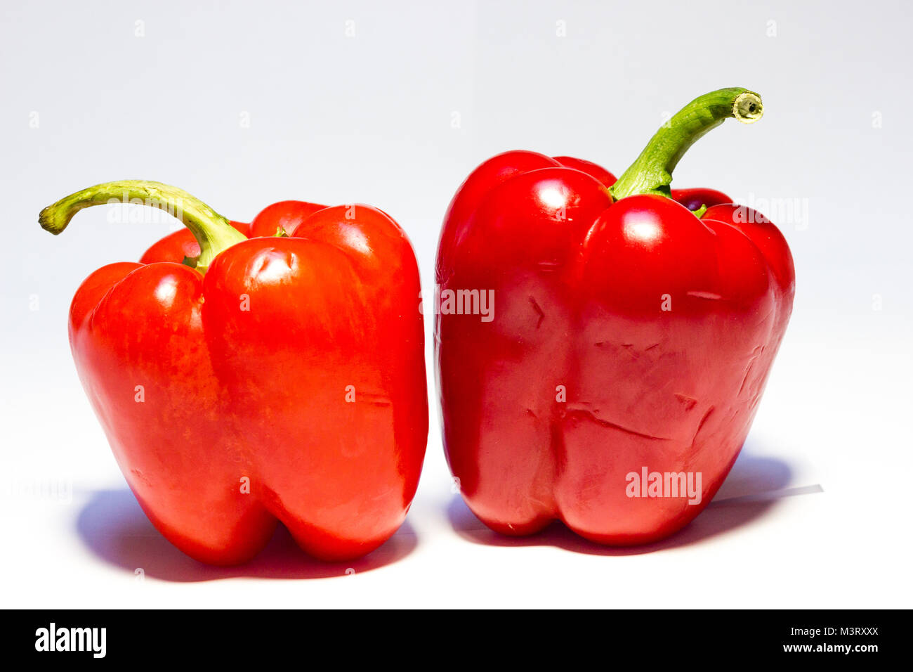 Two red bell peppers upright on white background Stock Photo - Alamy