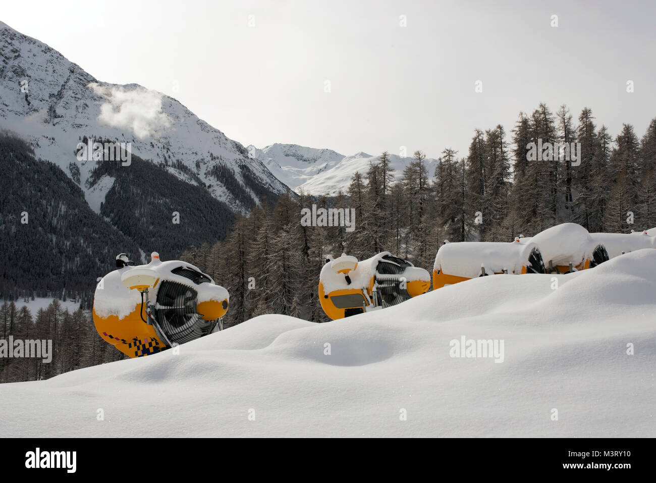 Snow making machines on top of the hill in the snow covered landscape ...