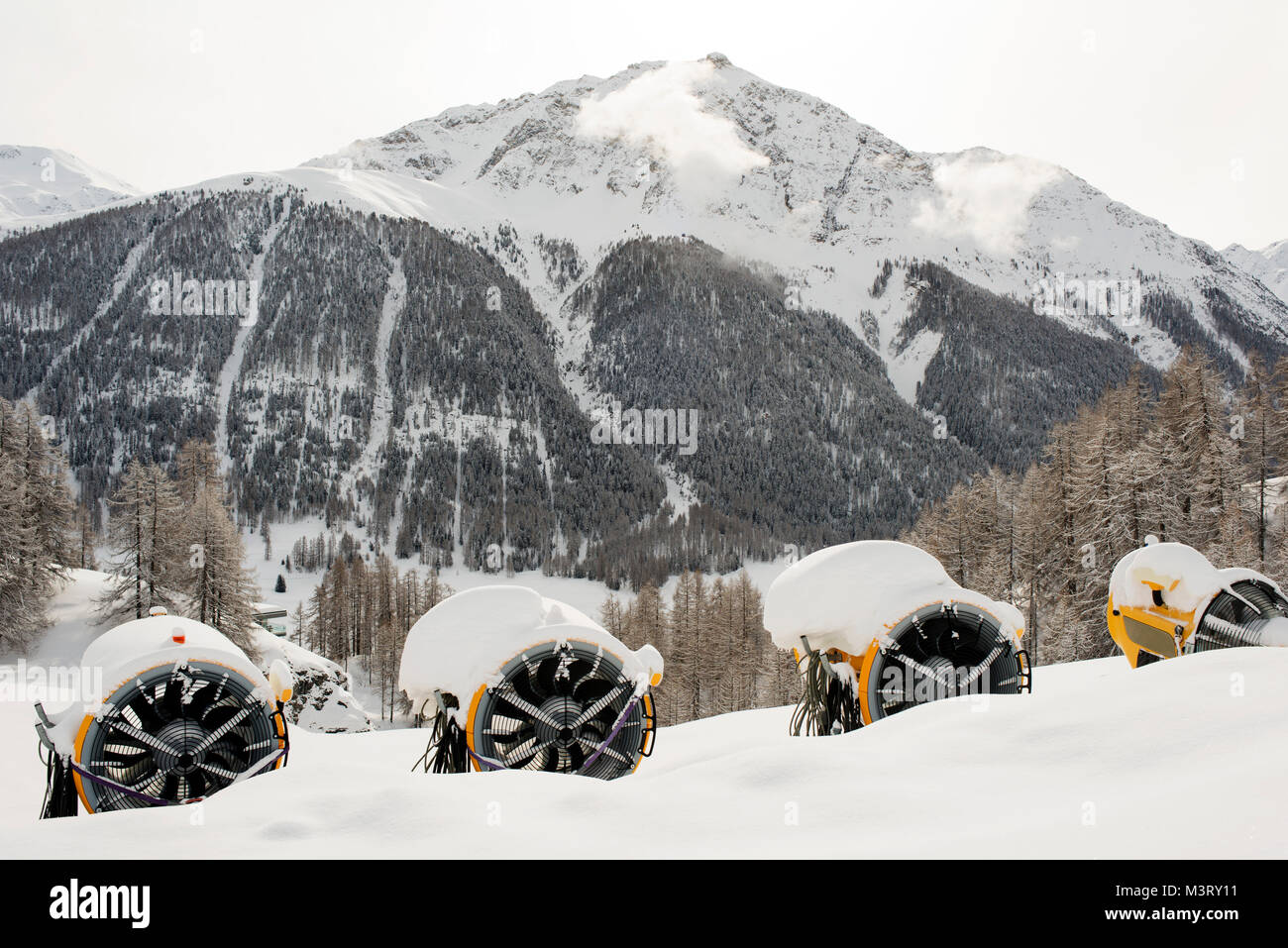 Snow making machines on top of the hill in the snow covered landscape ...