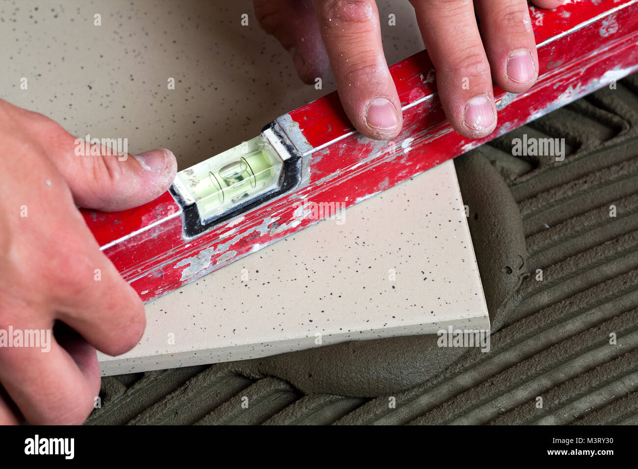 Ceramic tiles and tools for tiler. Worker hand installing floor tiles ...