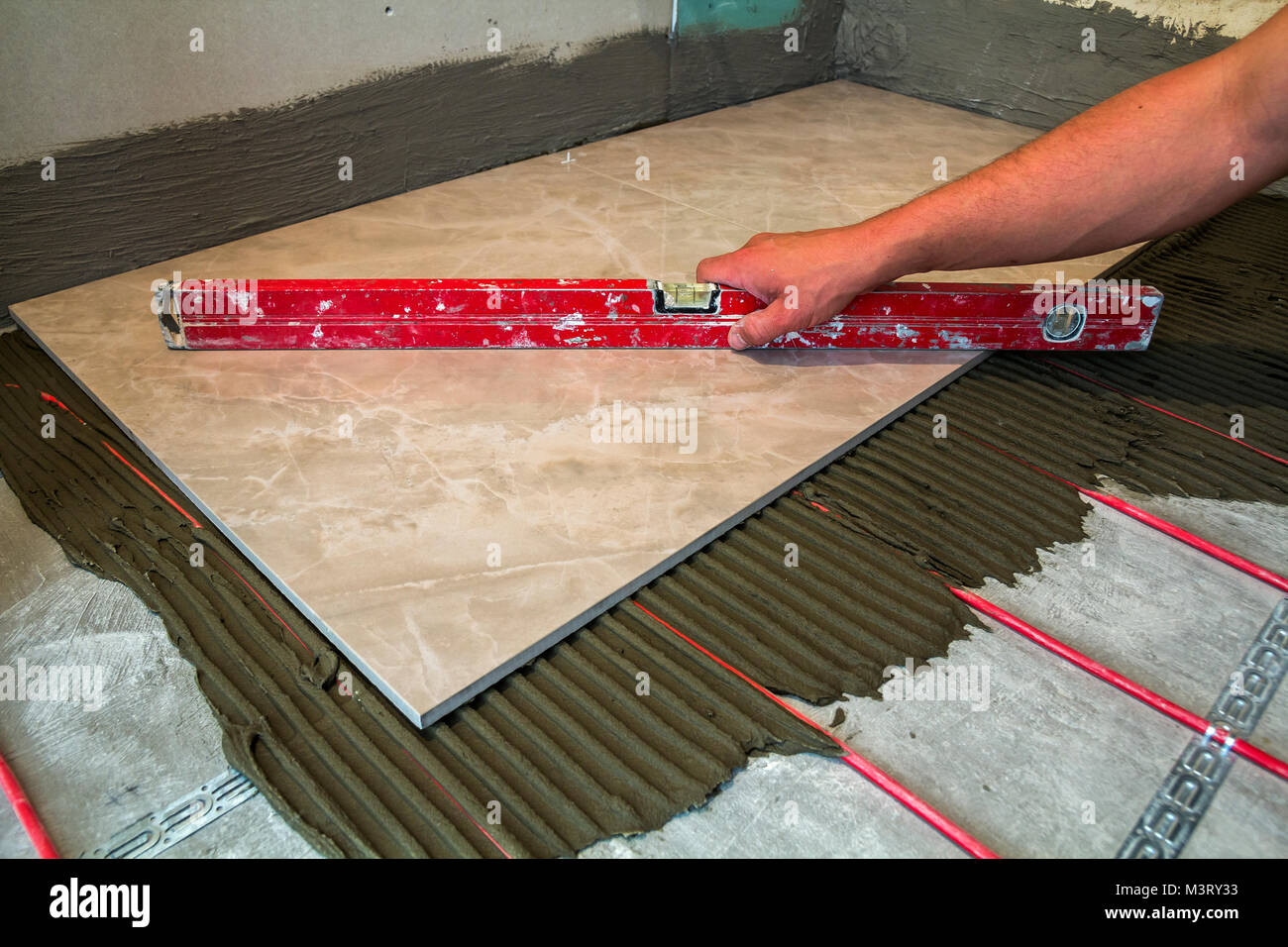 Ceramic tiles and tools for tiler. Worker hand installing floor tiles ...