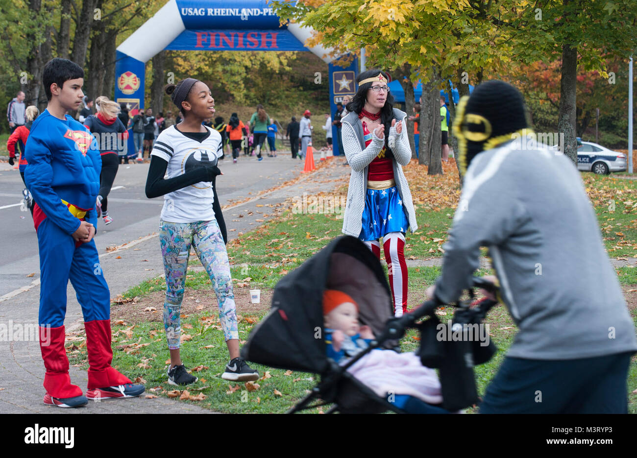 Participants in a Red Ribbon Run Superhero 5k event cheer on runners as ...