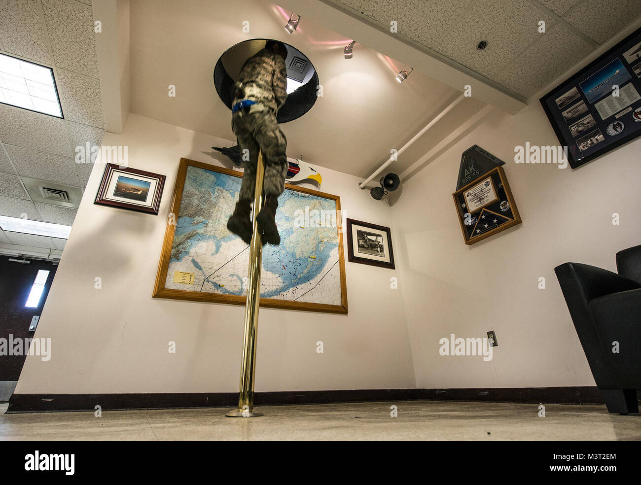 An F-22 Raptor maintainer slides down a pole to get to the first floor ...
