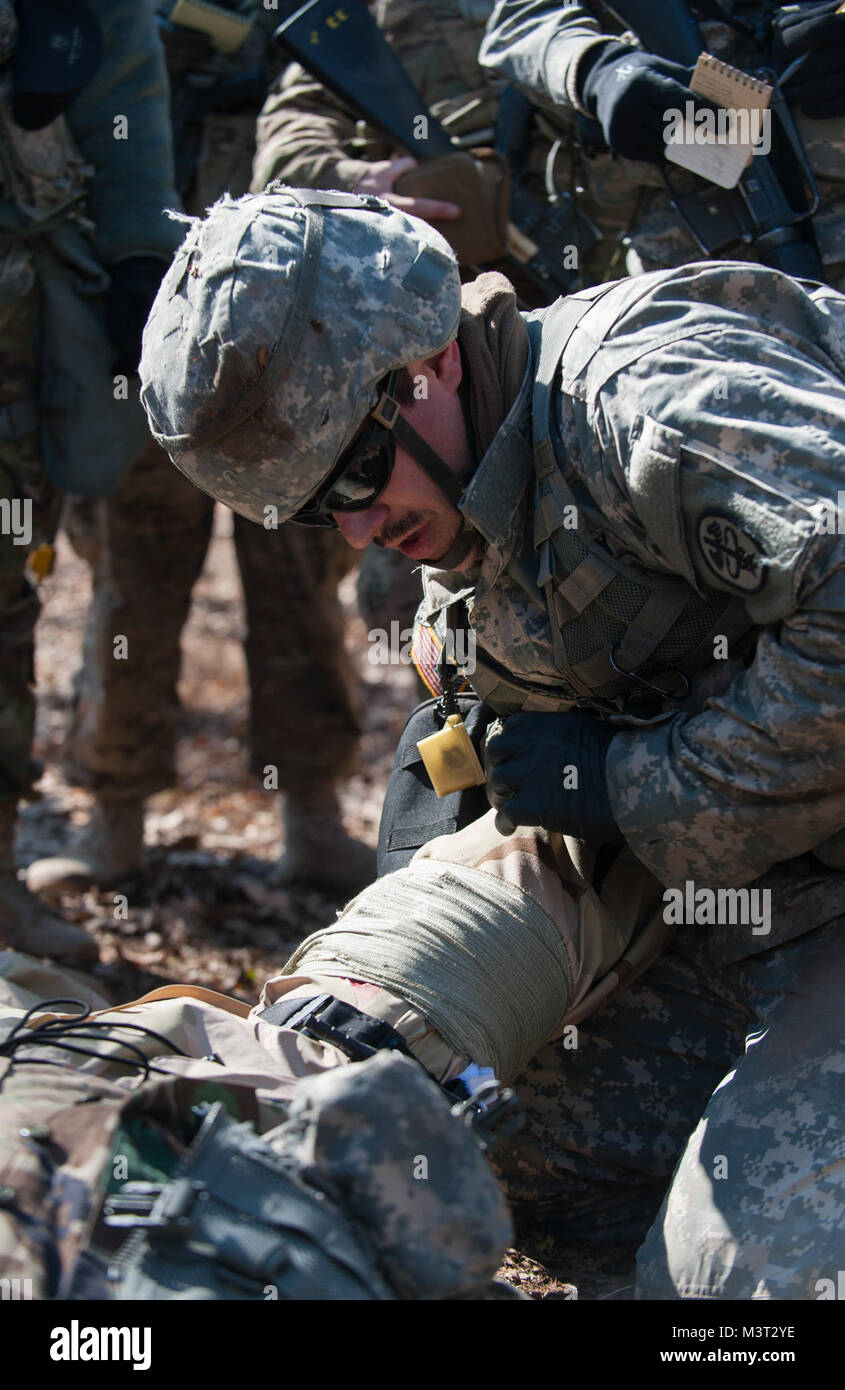 U.S. Army Sergeant Joshua Tabb, an EFMB evaluator, applies bandaging on ...