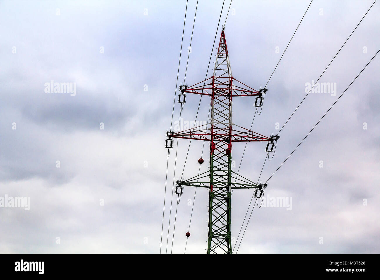 Pylons and power lines with vibrant sky, clouds and sun. High voltage ...