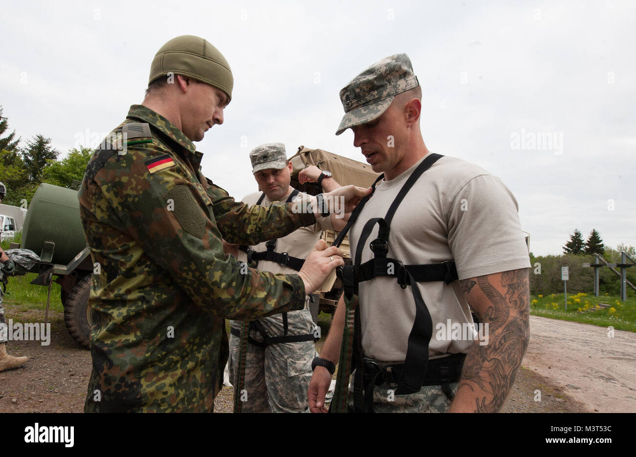A Soldier with the German Bundeswehr assists a U.S. Army Soldier with ...