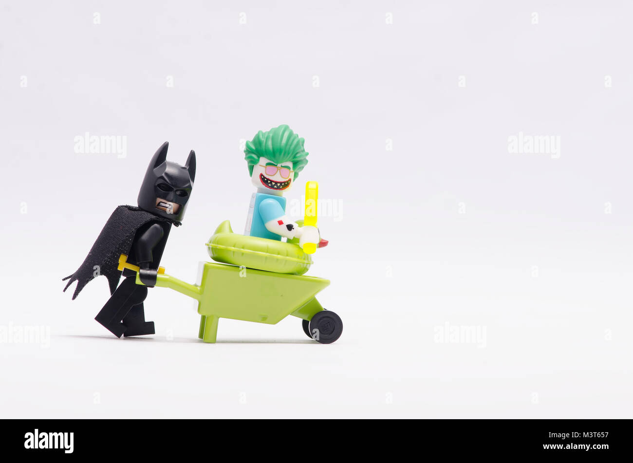 lego batman pushing wheelbarrow while joker sitting in it. isolated on ...