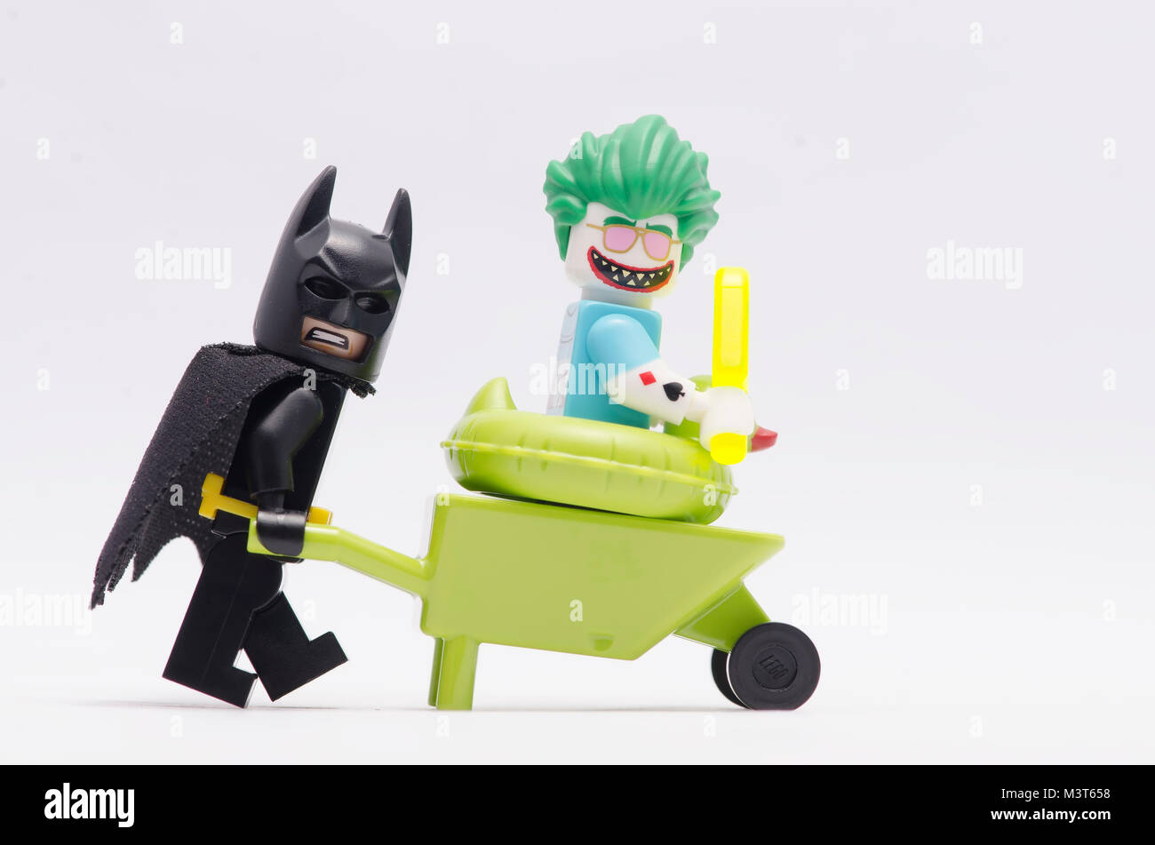 lego batman pushing wheelbarrow while joker sitting in it. isolated on ...