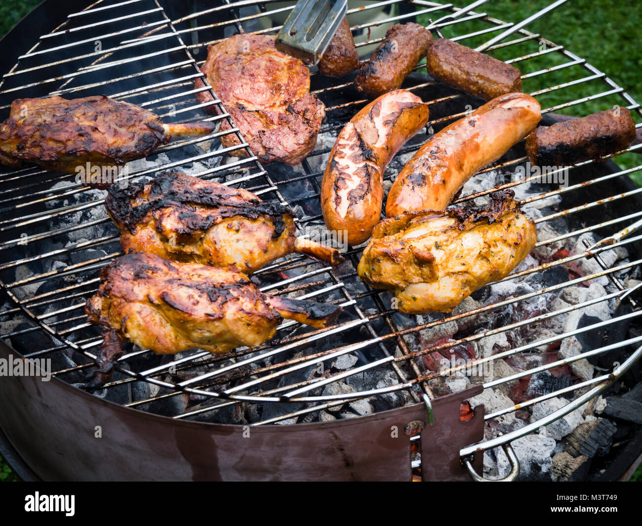 View from above onto a variety of roast meat and sausages on a barbecue ...