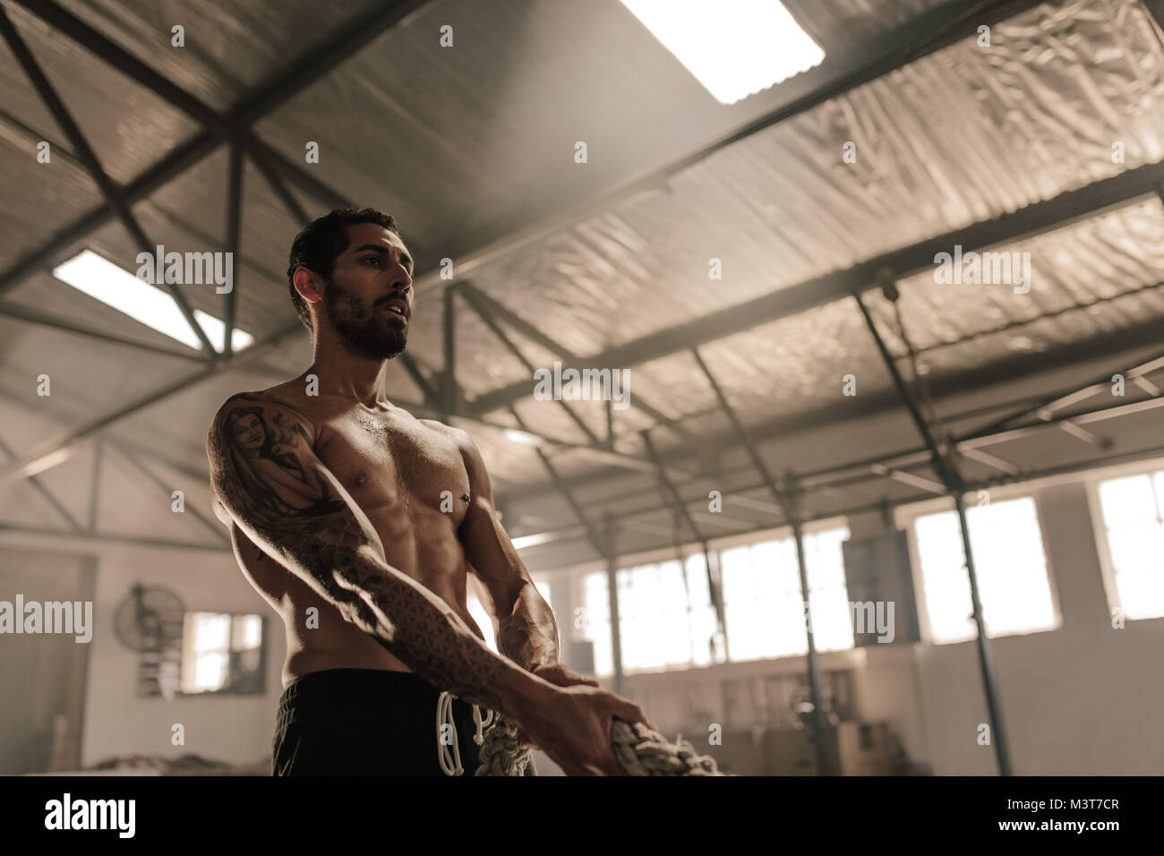 Muscular man exercising with heavy rope at health club. fitness male ...