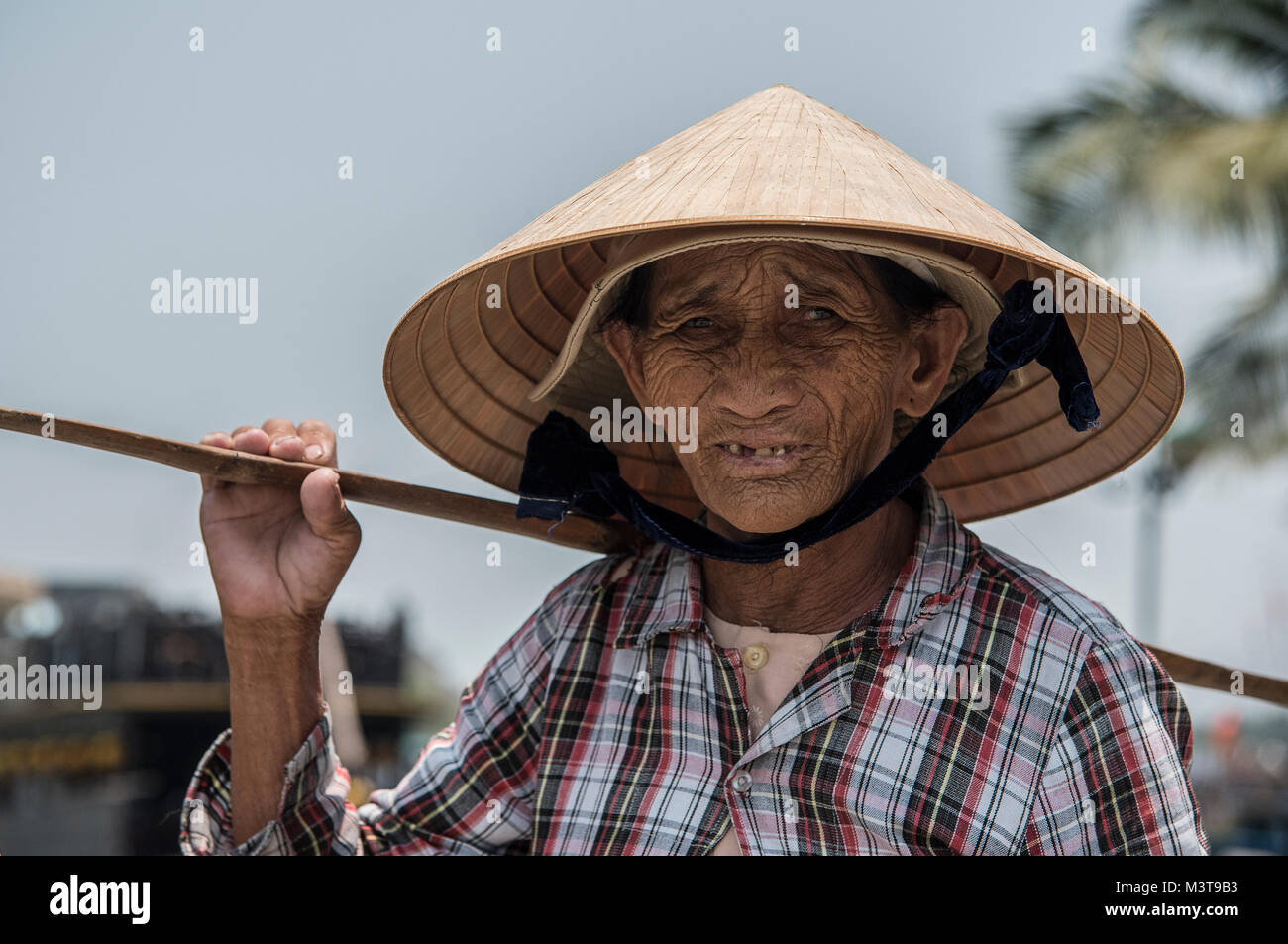 Vietnamese traditional old lady carrying bamboo yoke in Hoi An ...