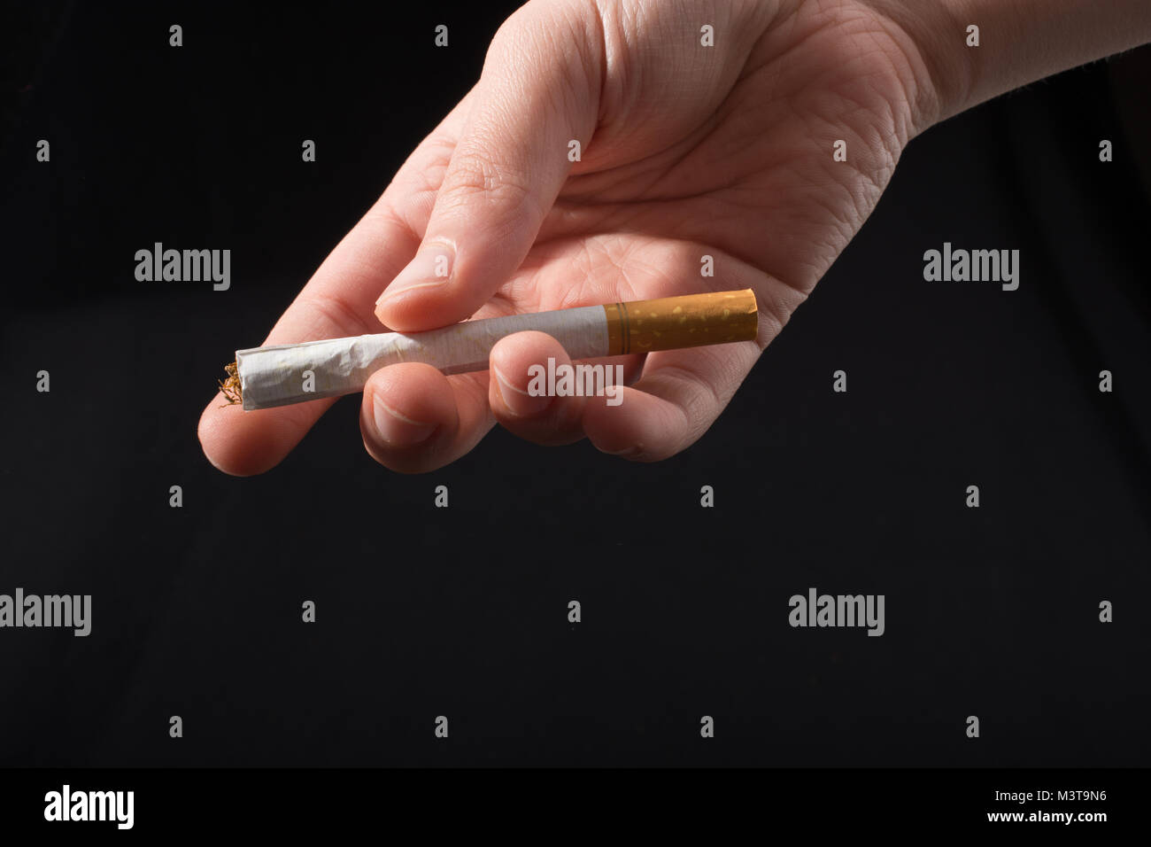 Hand is giving out cigarette on a black background Stock Photo - Alamy