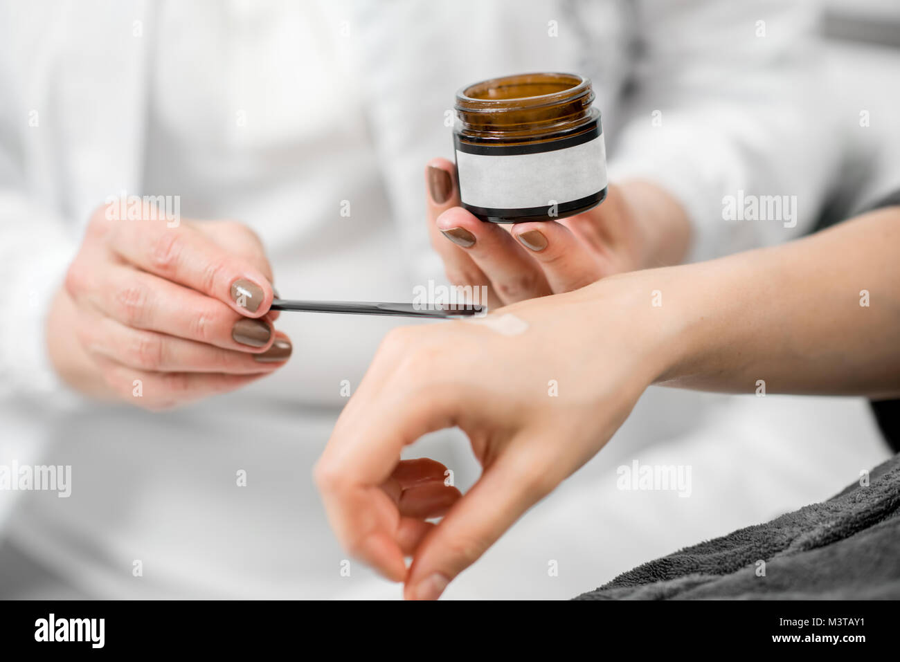 Doctor applying cream to a young client Stock Photo - Alamy