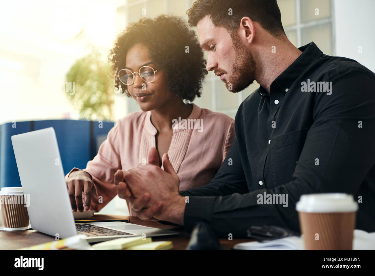 Two diverse colleagues working online together with a laptop while ...