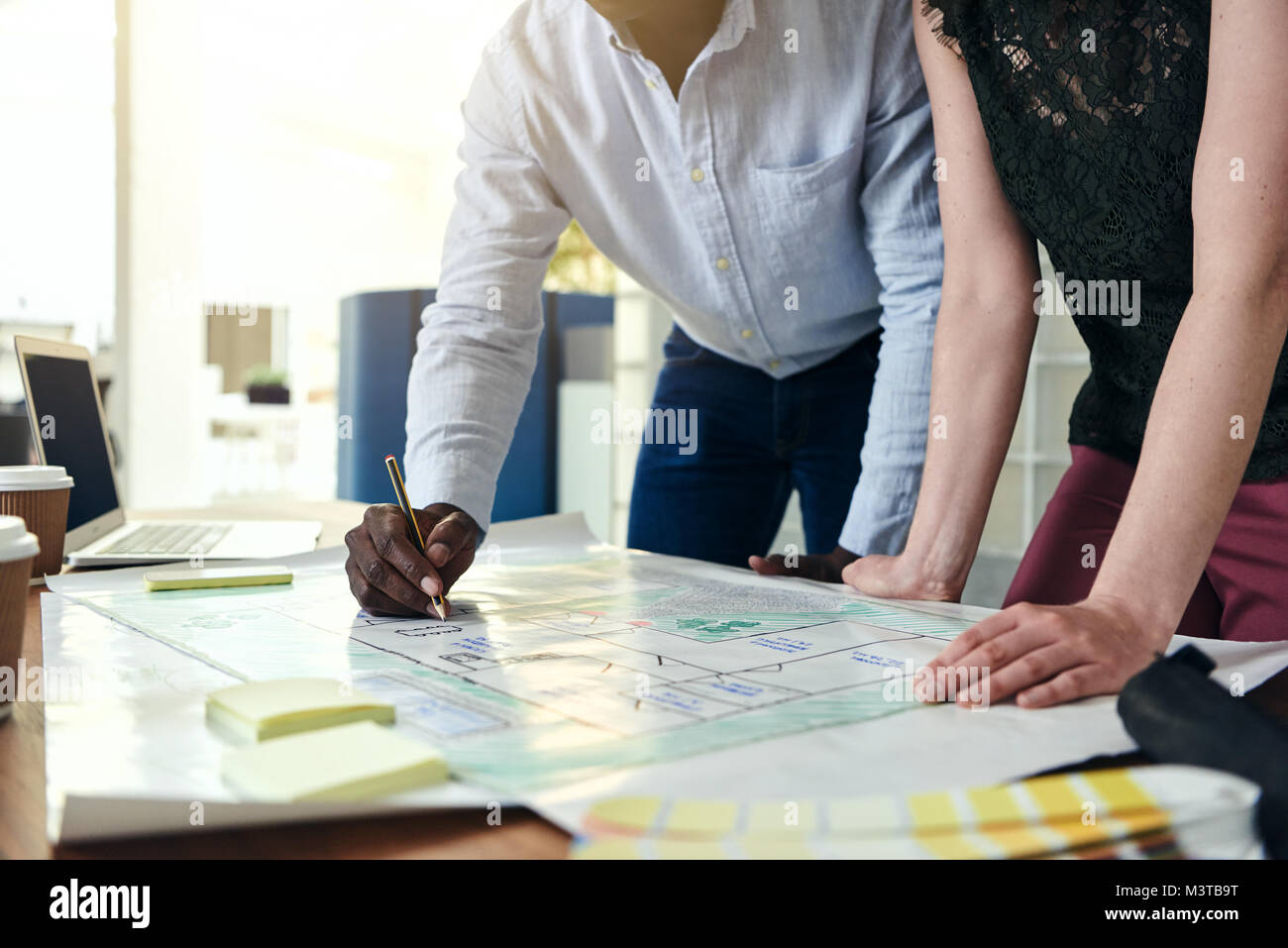 Two architects leaning on a table discussing a building design while ...
